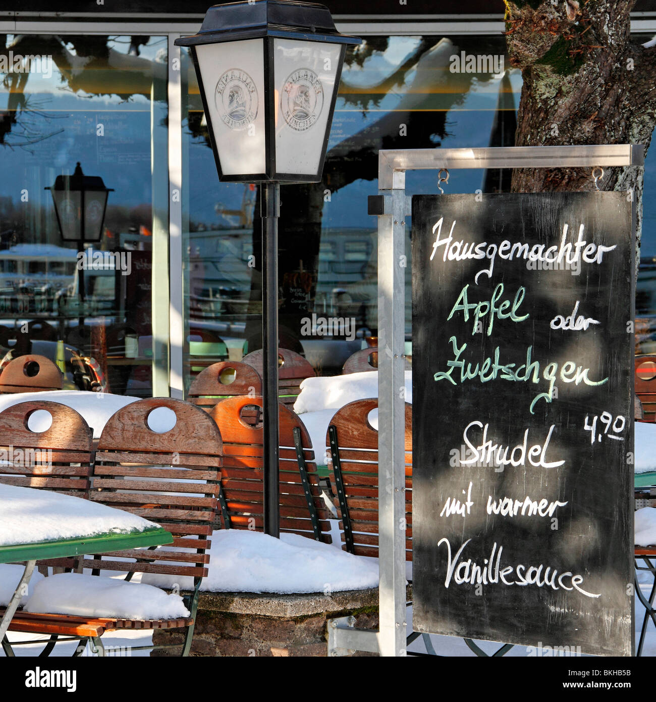 Snow covered tables and chairs with a blackboard food menu written in ...