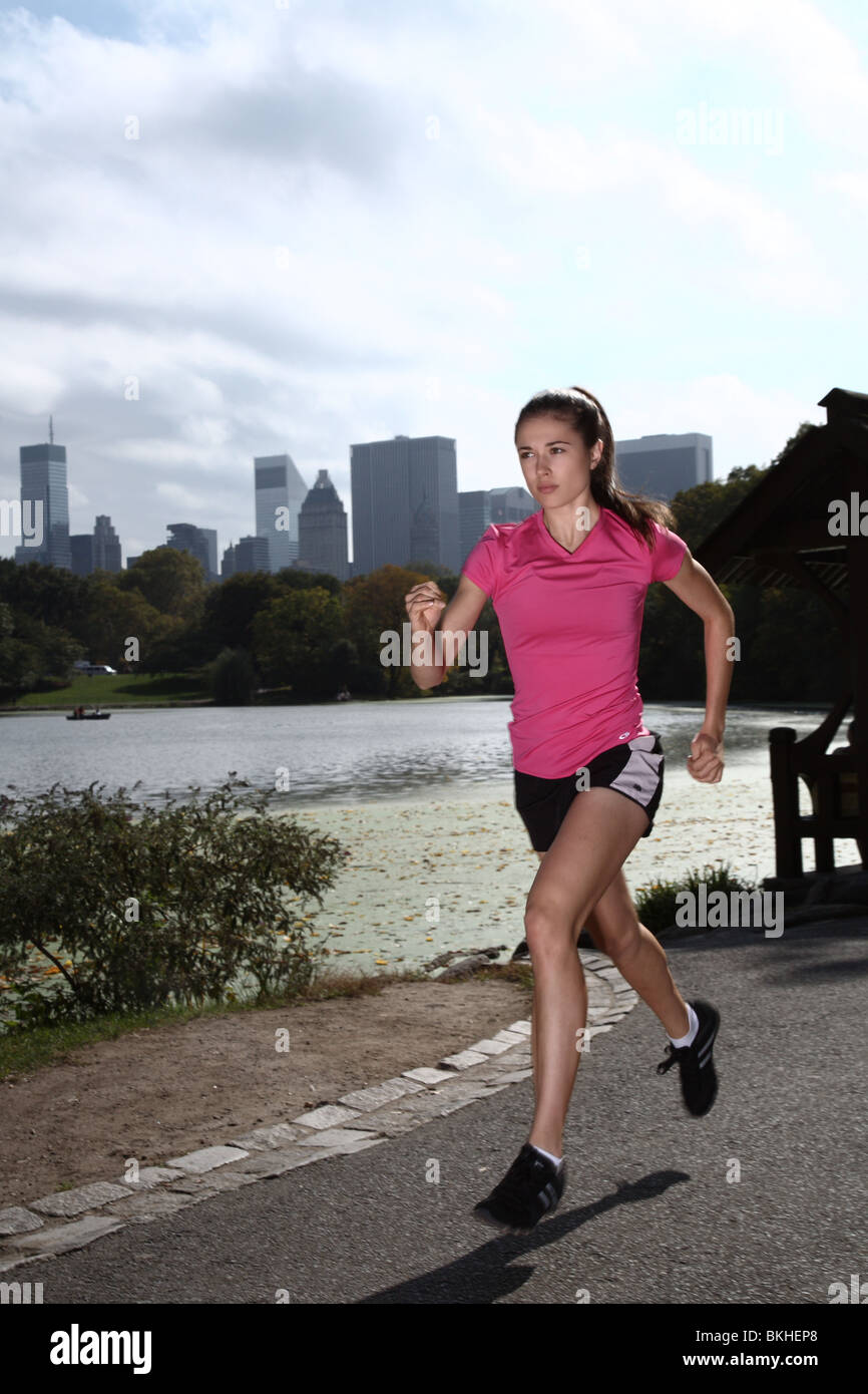 Woman jogging by river with city background Stock Photo - Alamy