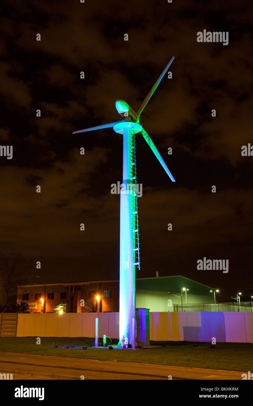 small wind power generator at night lit by coloured lights on ...