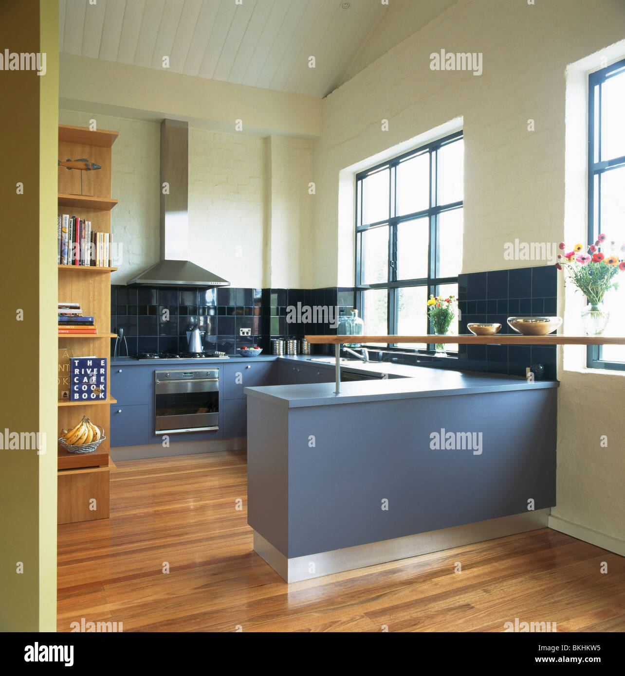 Fitted blue units in modern white kitchen with wooden flooring Stock ...