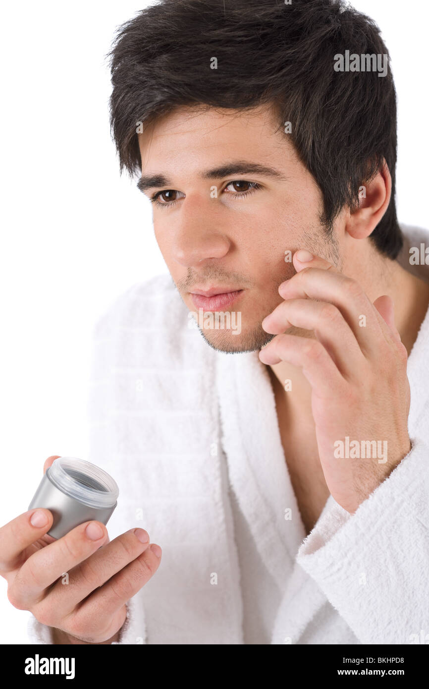 Facial care - Young man applying moisturizer on white background Stock ...