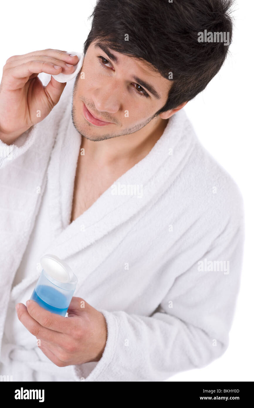 Facial care - Young man cleaning face with lotion on white background ...
