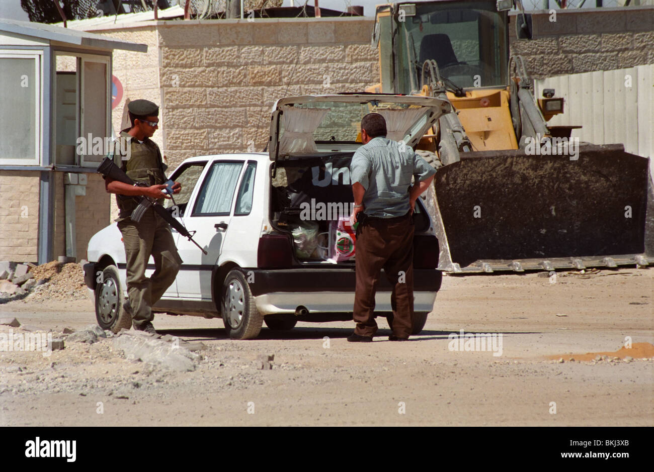 An Israeli soldier searches the car of a Palestinian man at a military ...