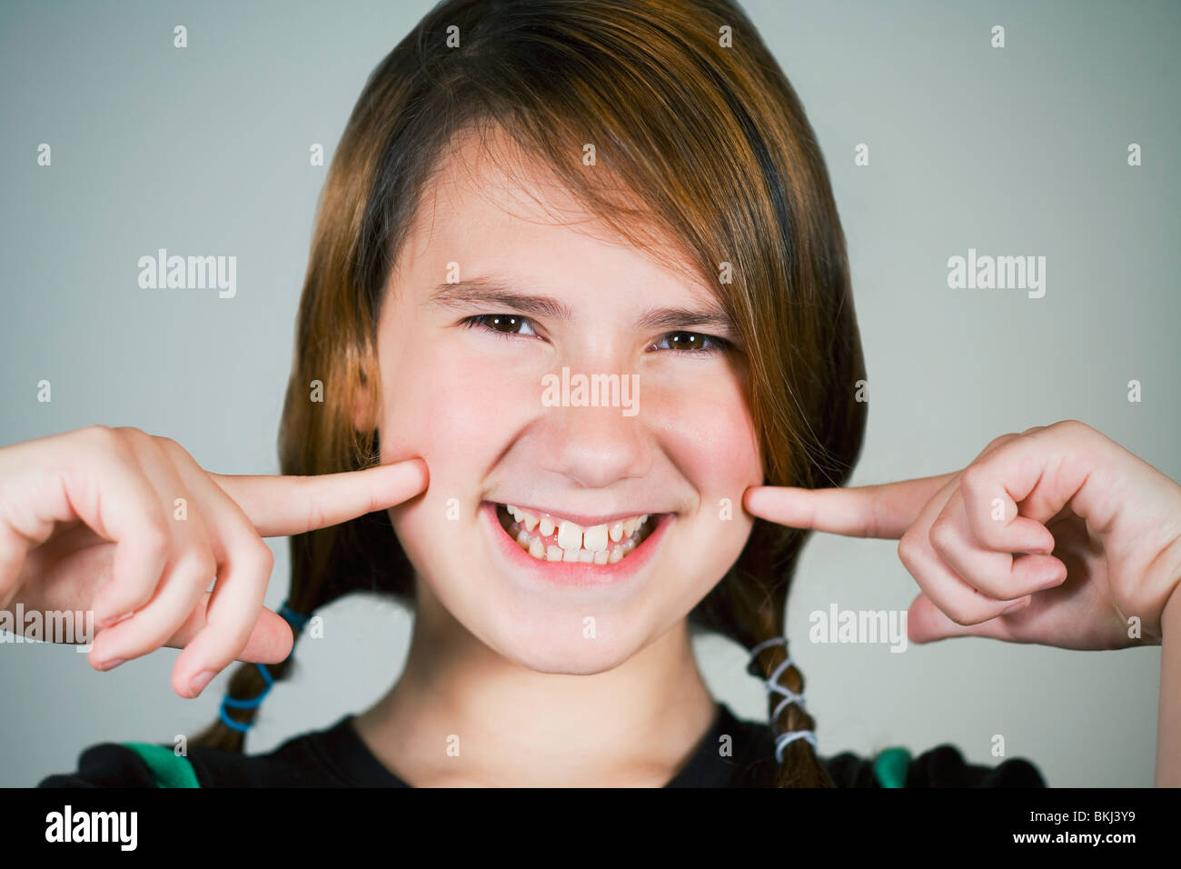 Portrait Of A Girl Pointing To Her Cheeks And Smiling Stock Photo - Alamy
