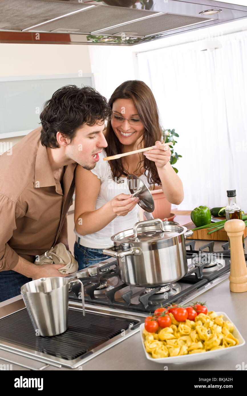 Couple cook in modern kitchen - man taste food Stock Photo - Alamy