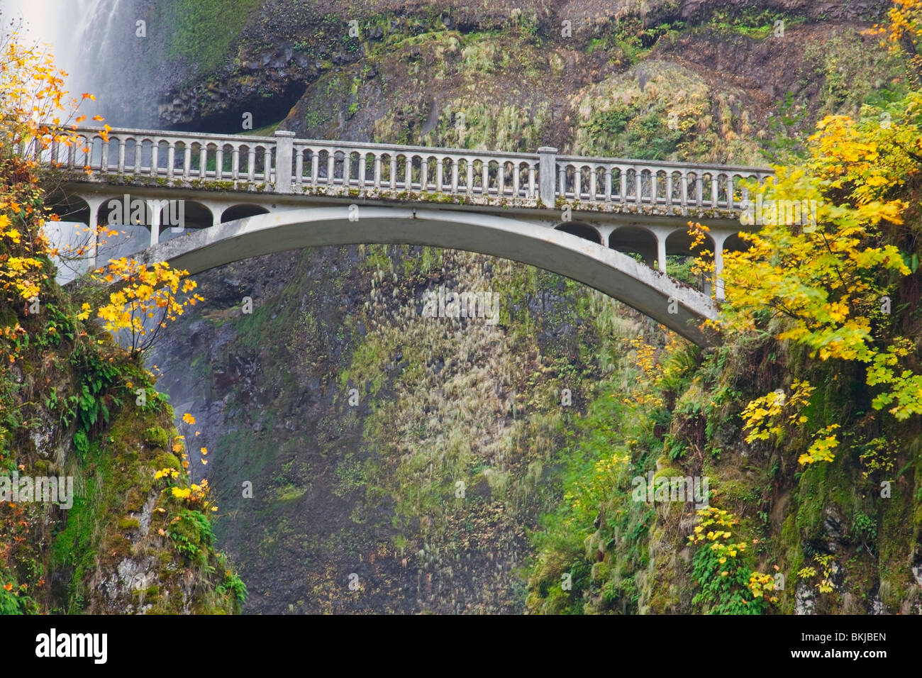 A Bridge Between Two Steep Slopes With A Waterfall Behind It Stock ...