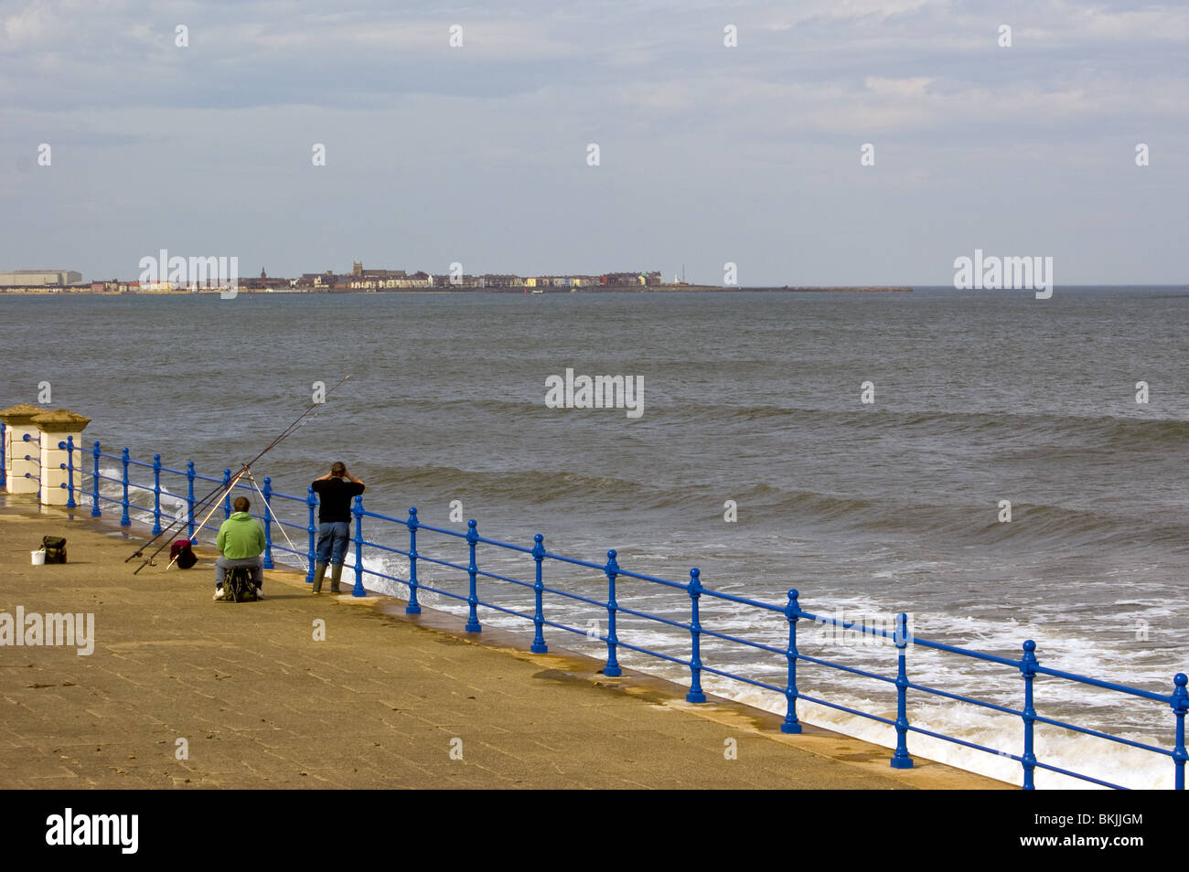 TWO MEN FISHING SEA ANGLING ON SEATON CAREW PROMENADE AS THE TIDE COMES ...