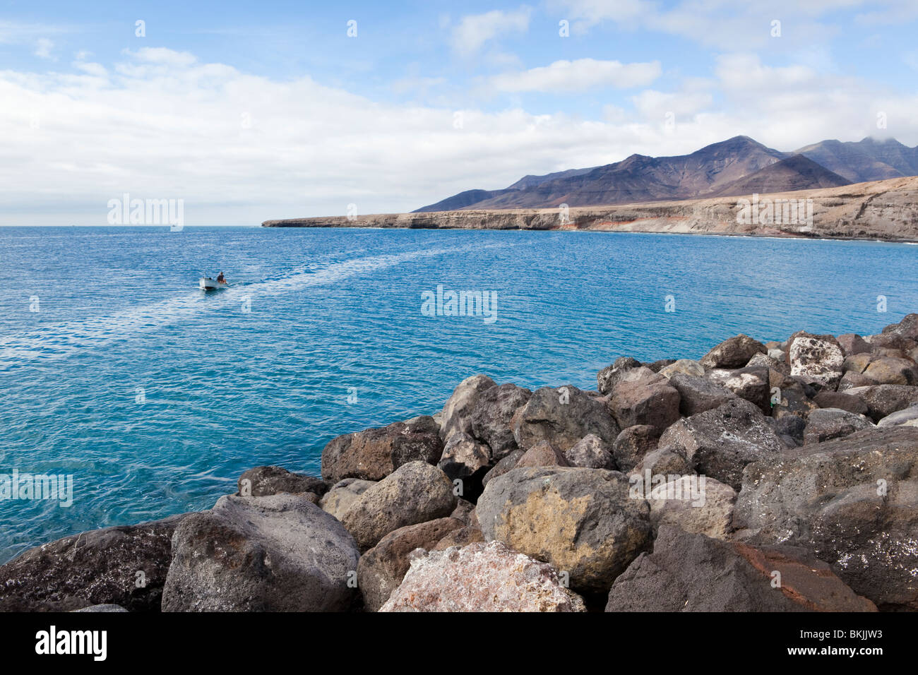 A fishing boat approaching the volcanic rock defences to the harbour at ...