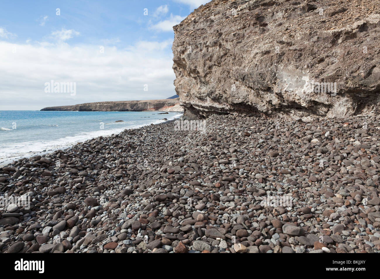 A beach of volcanic rock pebbles near the harbour at Morro del Jable ...
