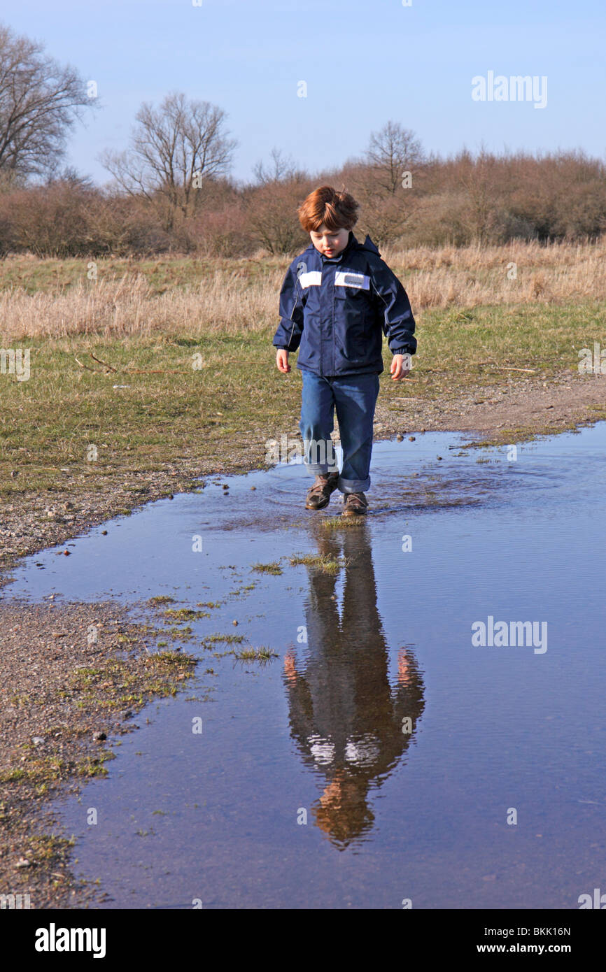 portrait of a young boy walking through a puddle Stock Photo - Alamy