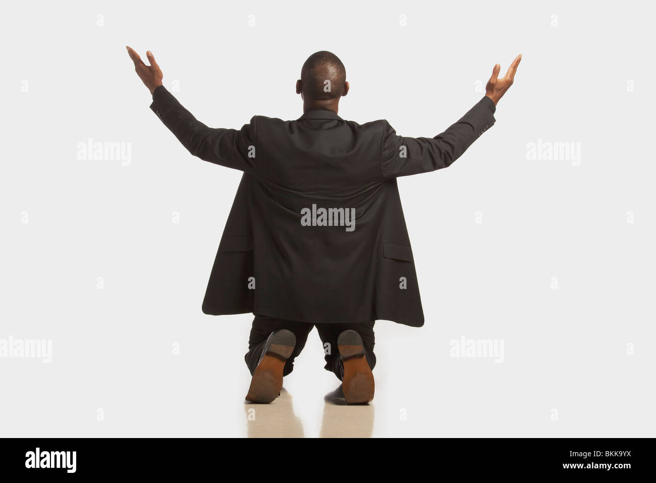 A Businessman Wearing A Black Suit Kneeling With Hands Raised Stock ...