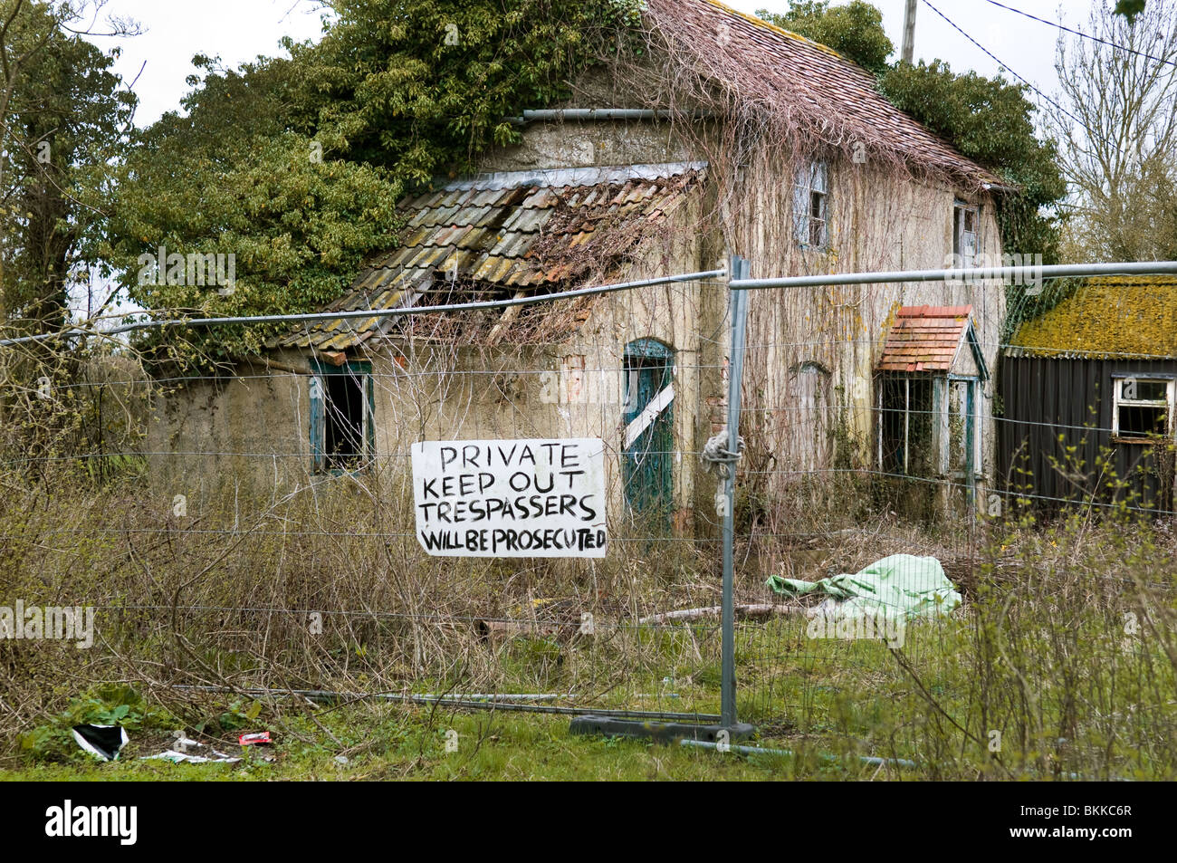Derelict , abandoned house behind high fence with keep out signs Stock ...