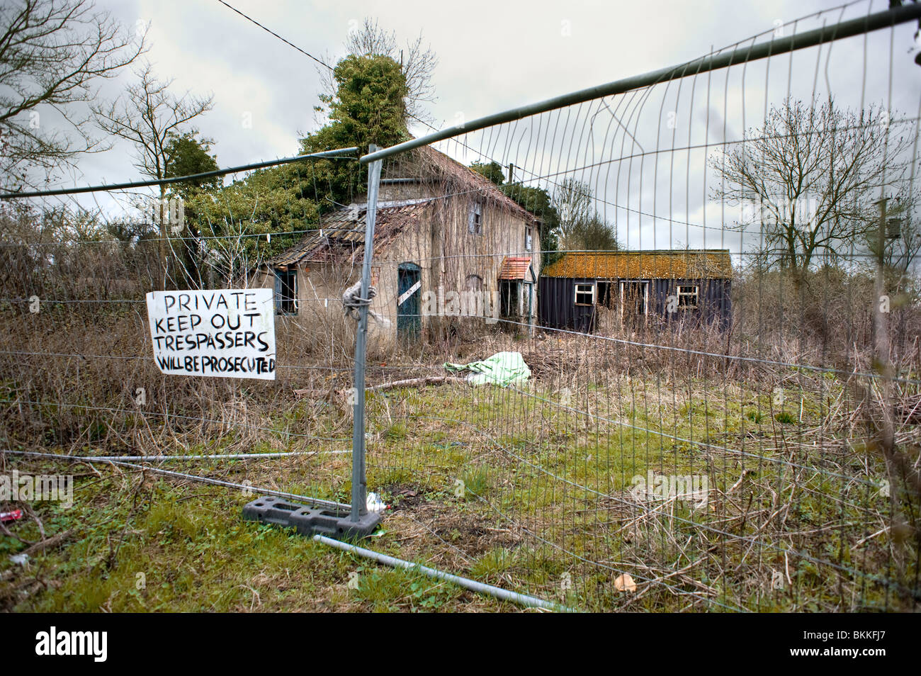 Derelict , abandoned house behind high fence with keep out signs Stock ...