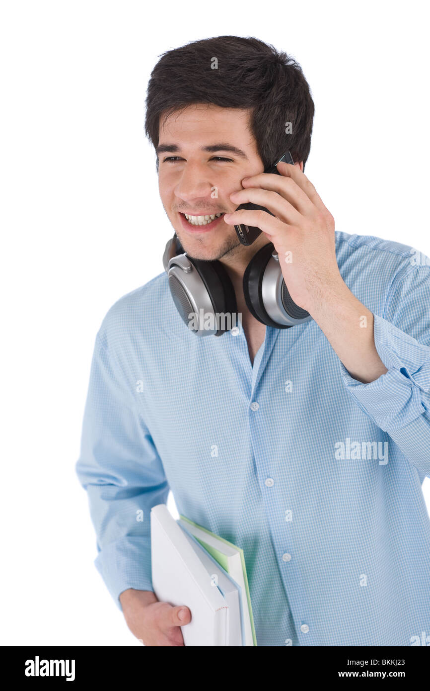 Male student calling with mobile phone holding books on white ...