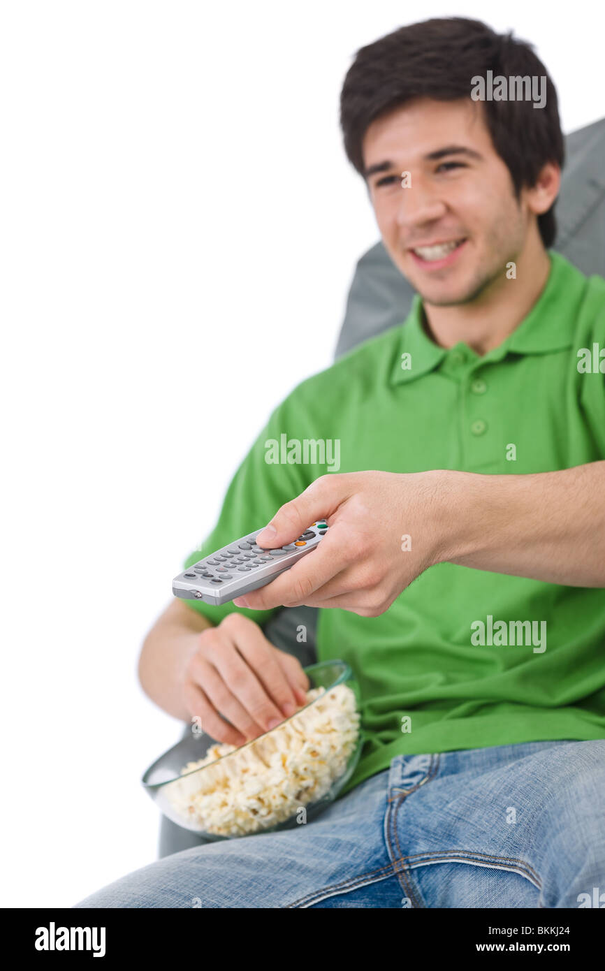 Young man holding remote control watch television and eat popcorn on ...