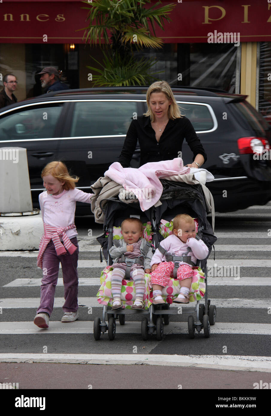 mother carrying two sons in a stroller or buggy with her elder girl ...