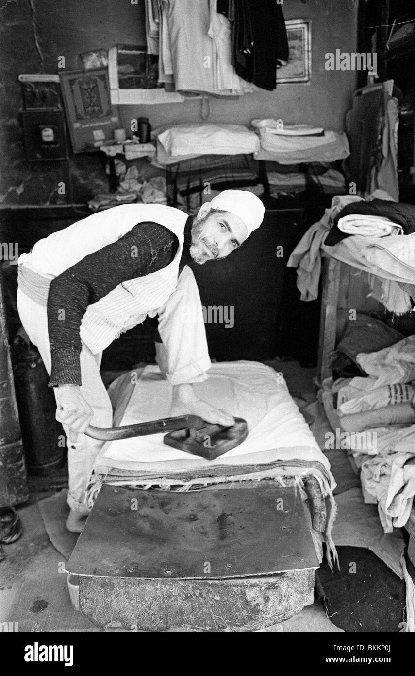 A laundry man ironing with the use of his feet in Mar Girgis, Coptic ...