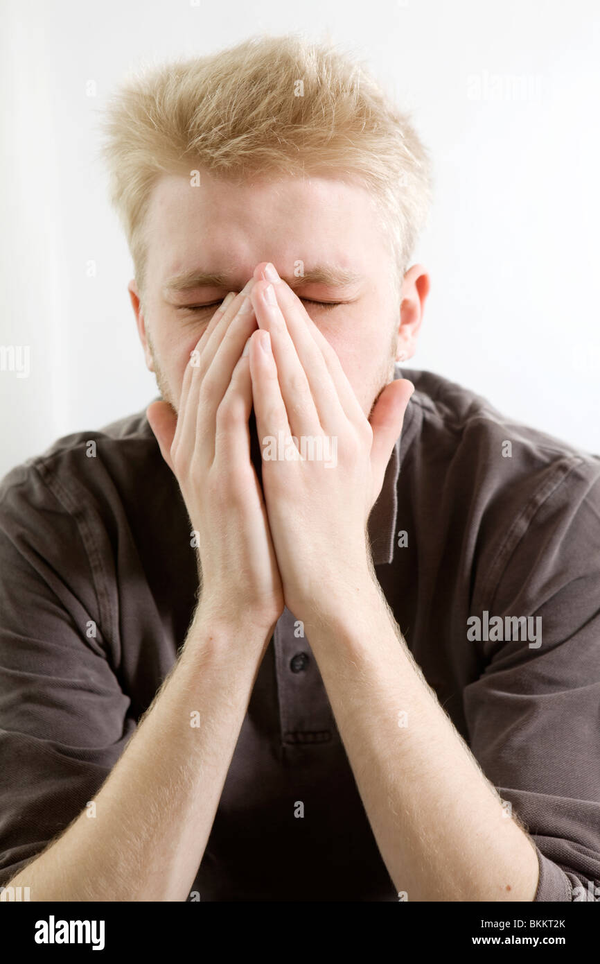 close up portrait of serious blond man closing his eyes by hands Stock ...