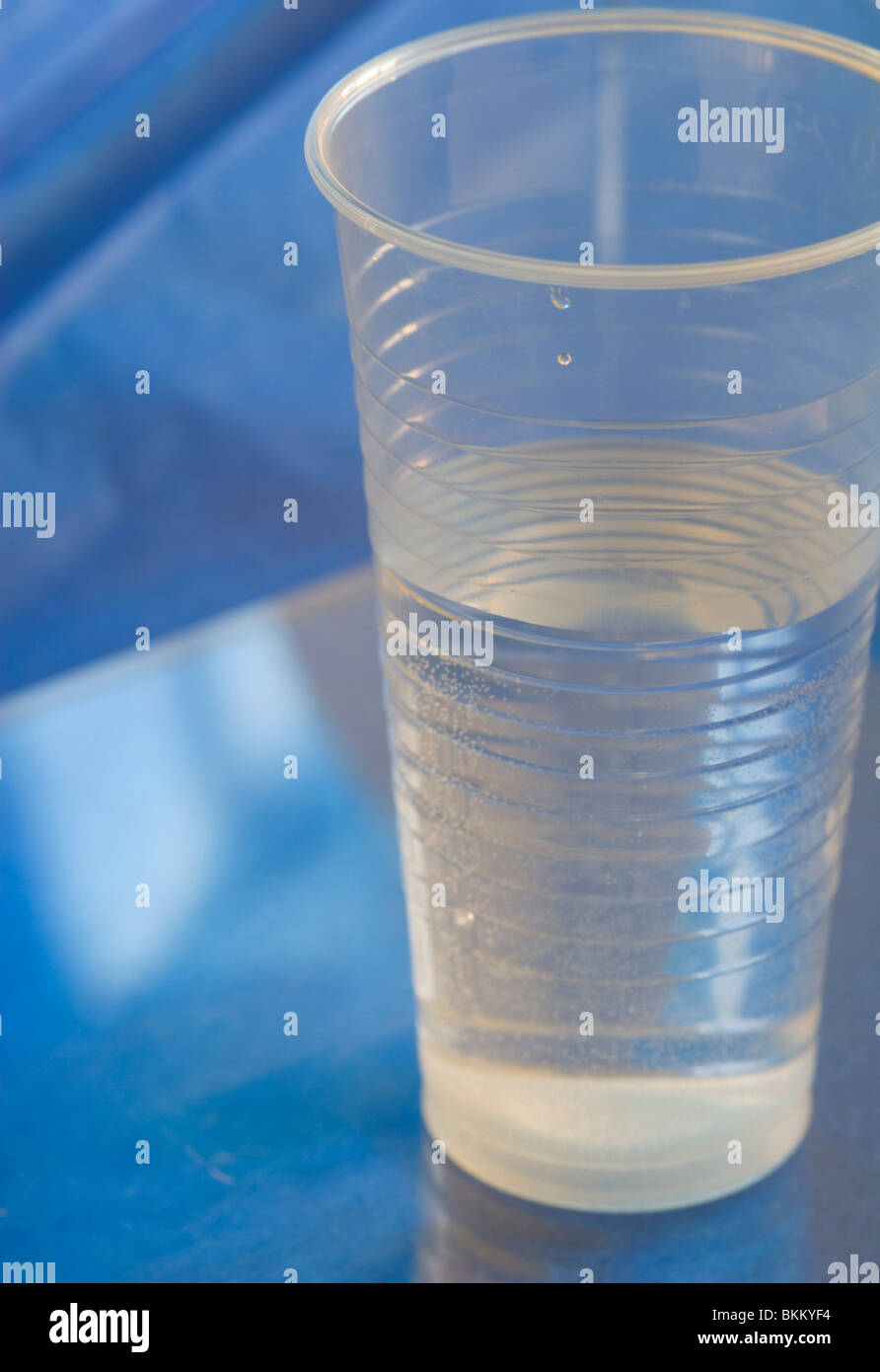 Water in a plastic cup against a blue background Stock Photo - Alamy