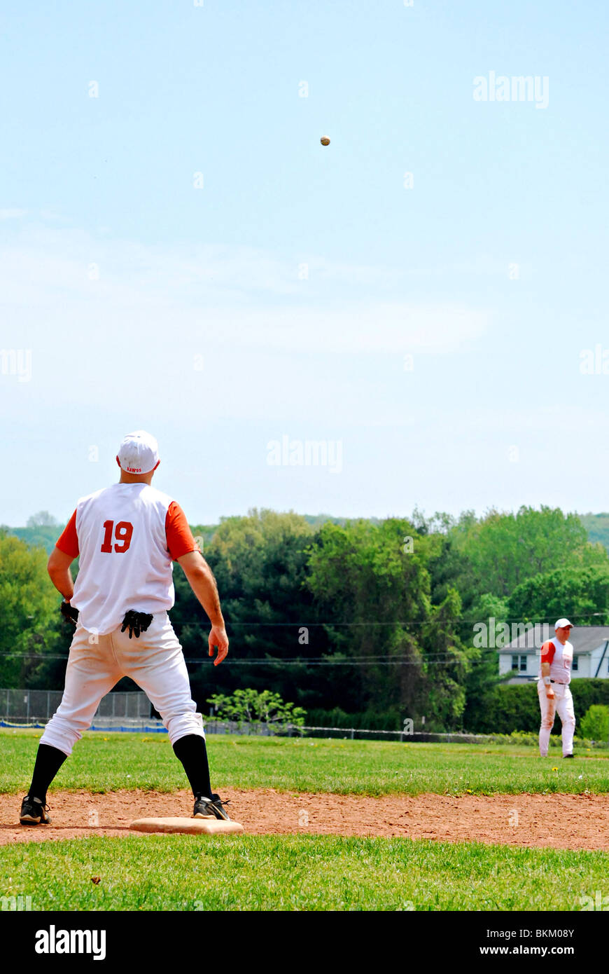 Mens baseball league. first baseman tries to get the runner out on ...