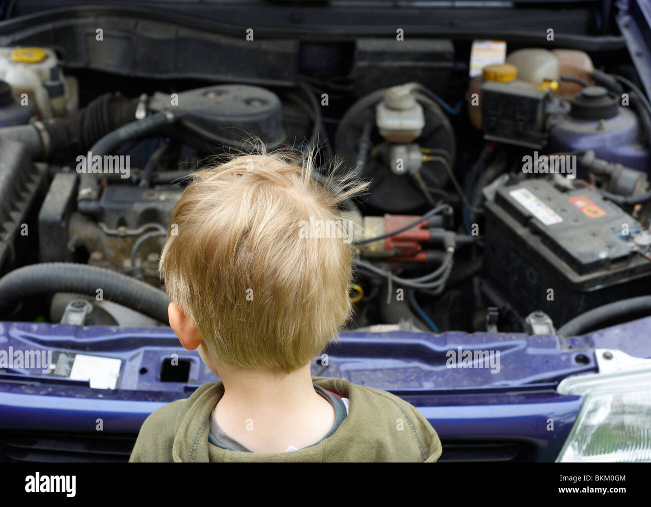 Child blond boy checking the condition of car engine Stock Photo - Alamy