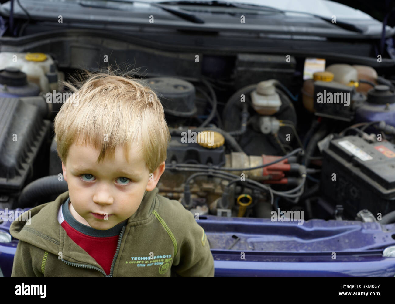 Child blond boy checking the condition of car engine Stock Photo - Alamy
