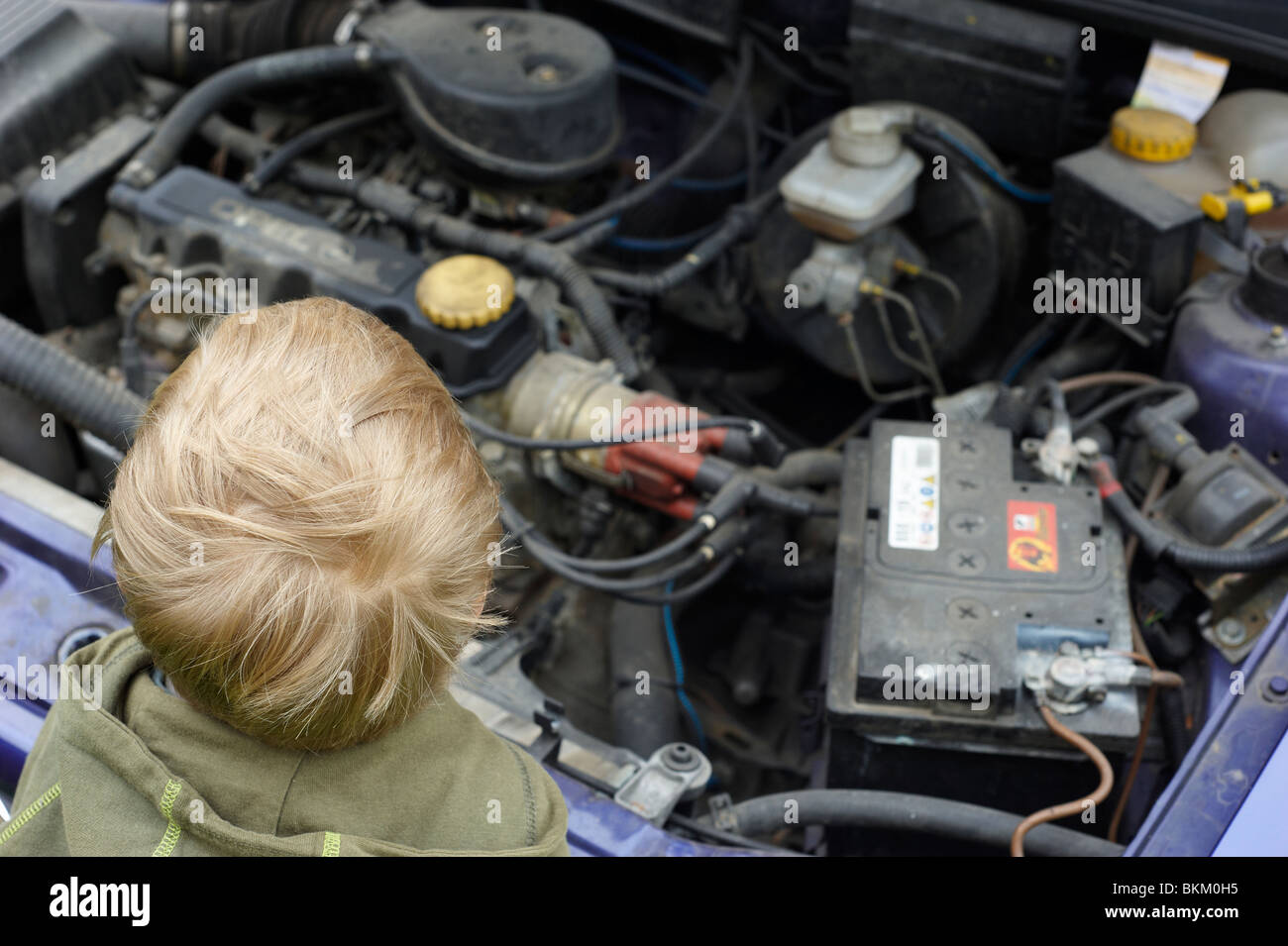 Child blond boy checking the condition of car engine Stock Photo - Alamy