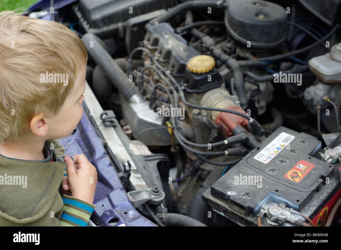 Child blond boy checking the condition of car engine Stock Photo - Alamy