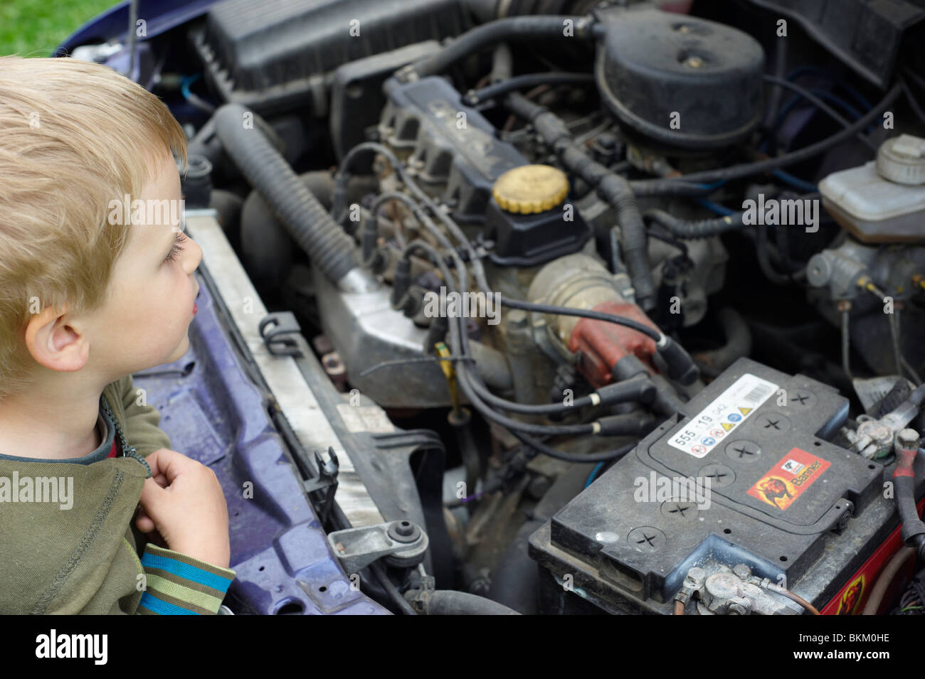 Child blond boy checking the condition of car engine Stock Photo - Alamy