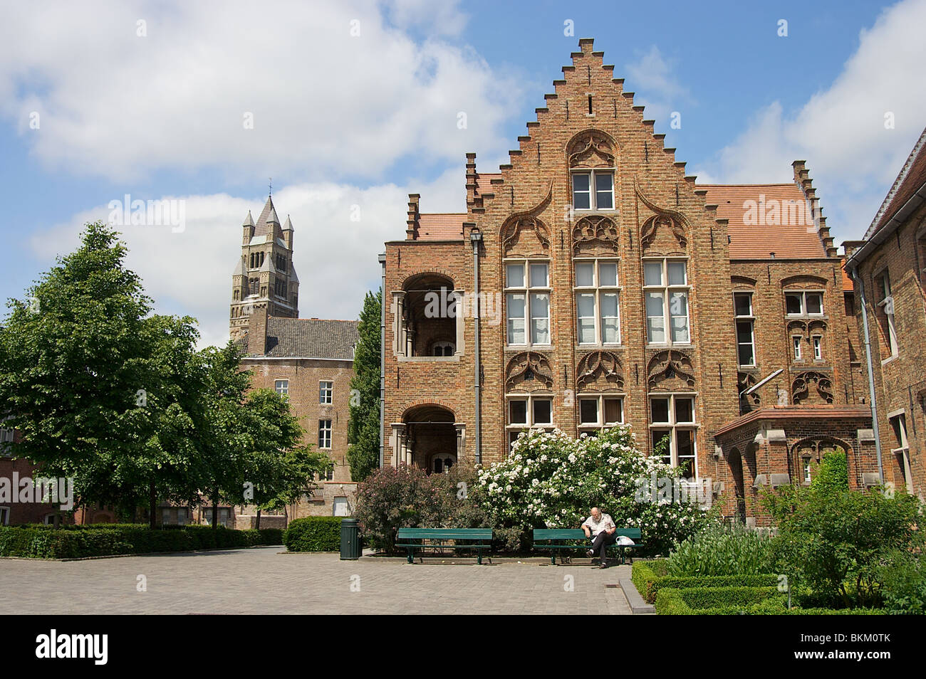 A man sits on a bench near brick buildings in Bruges, Belgium Stock ...