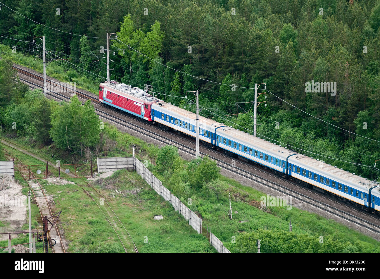 Red, blue passenger Russian train between lakes. Top view. Long ...