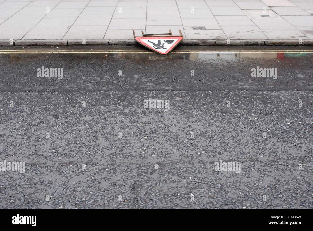 Conceptual image of man at work sign fallen over at road side ...