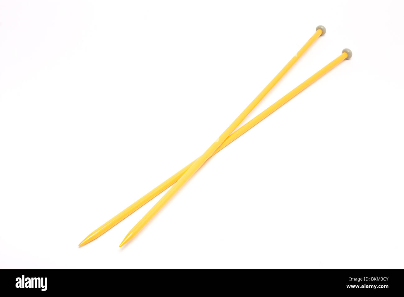 A pair of large Yellow Knitting Needles isolated against white ...