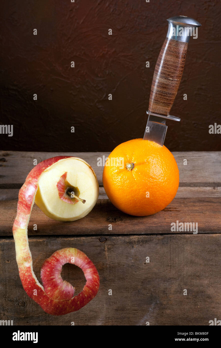 Peeled apple and a dagger cutting an orange Stock Photo - Alamy