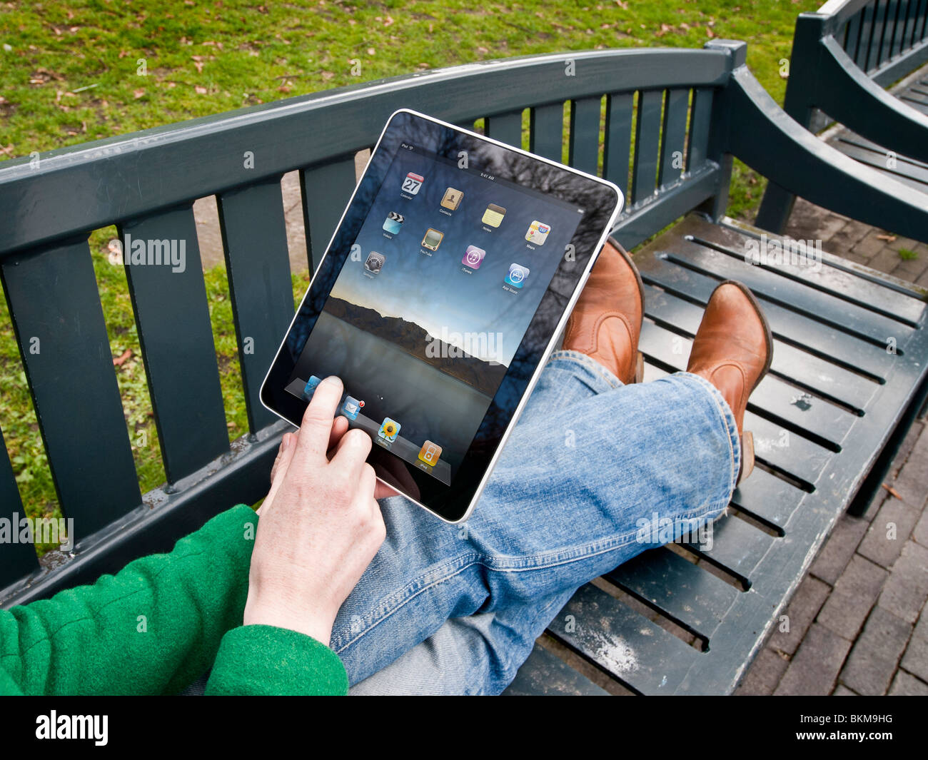 Woman on park bench using Apple iPad touchscreen tablet computer ...