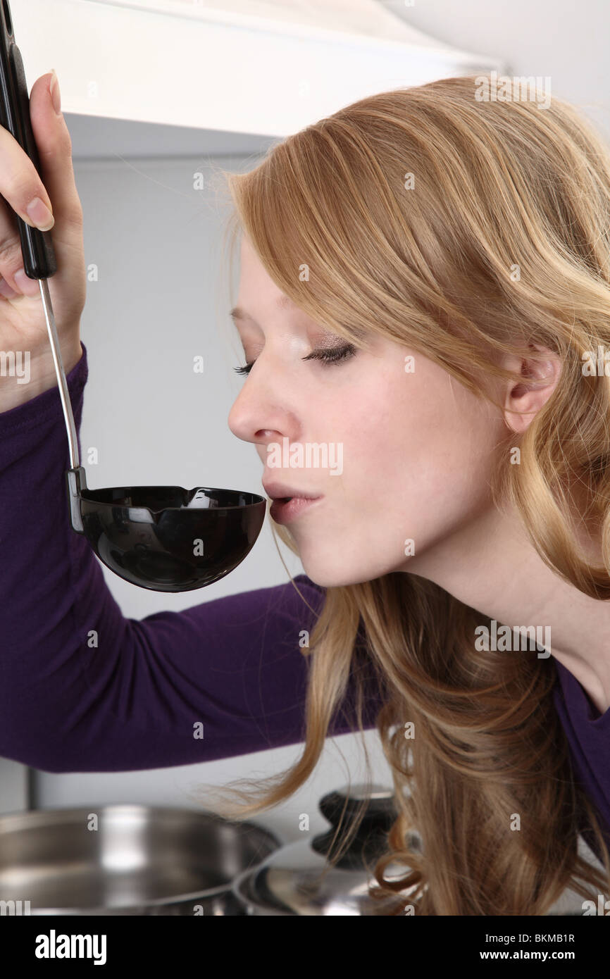 Young woman taste testing her cooking Stock Photo - Alamy