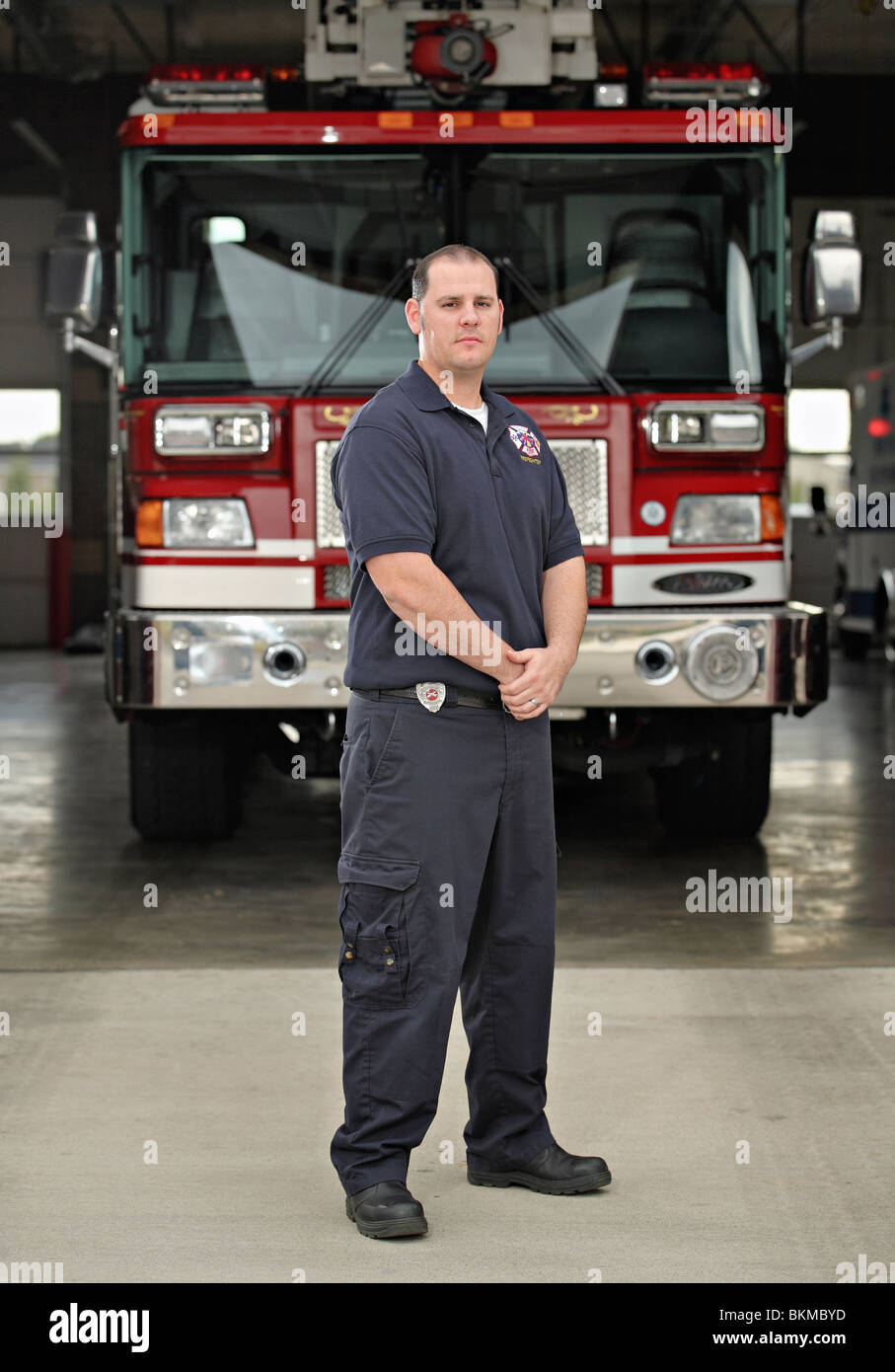 full-length fireman standing in front of fire engine at firehouse ...