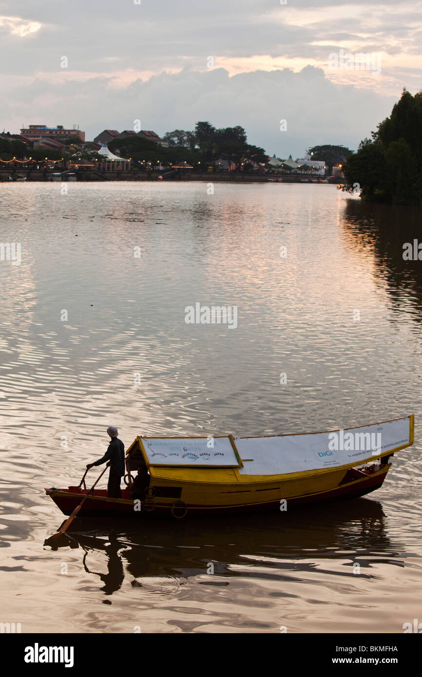 A tambang (sampan water taxi) is silhouetted on the Sarawak River at ...