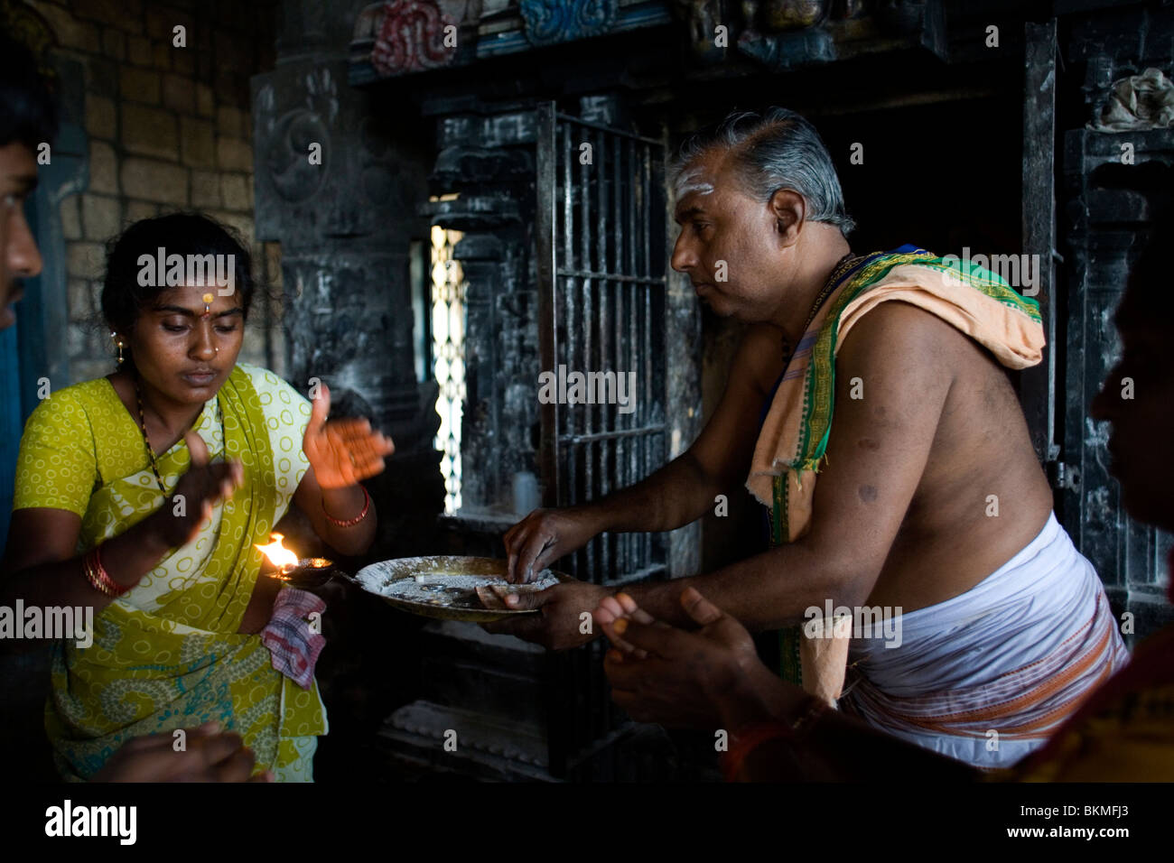 A priest by a shrine at the Murugan temple, gives ritual blessings to ...