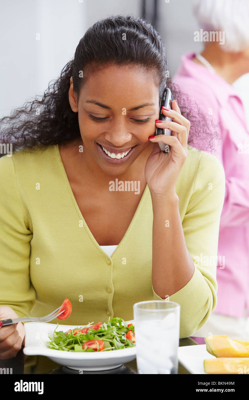 African American woman eating salad and talking on cell phone Stock ...