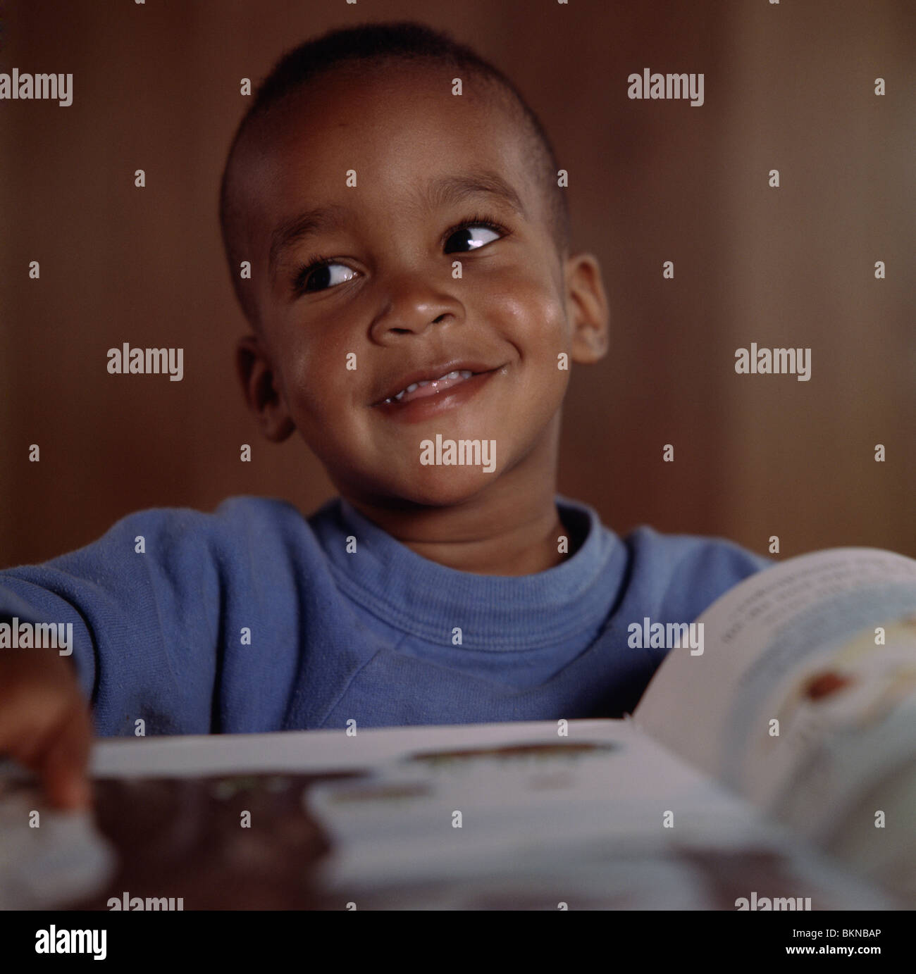 Young African American boy smiling sitting in front of an open book ...
