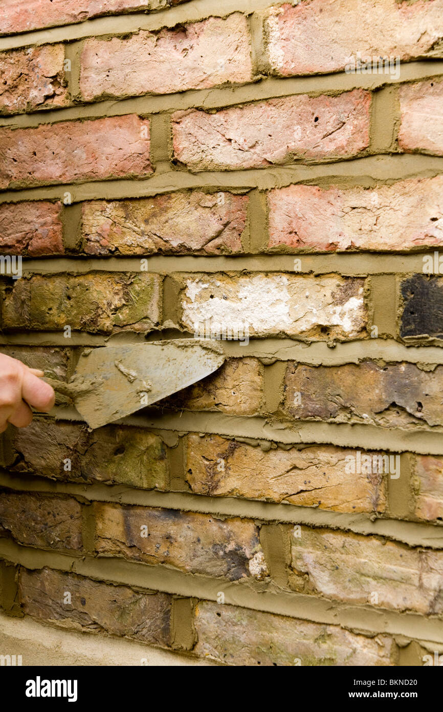 A brick wall being re-pointed / pointing a wall Stock Photo - Alamy