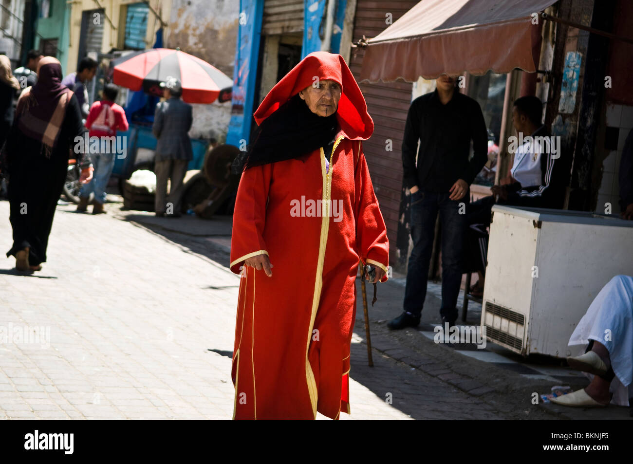 Market scene in Morocco. A woman wearing a traditional red Jalaba dress ...