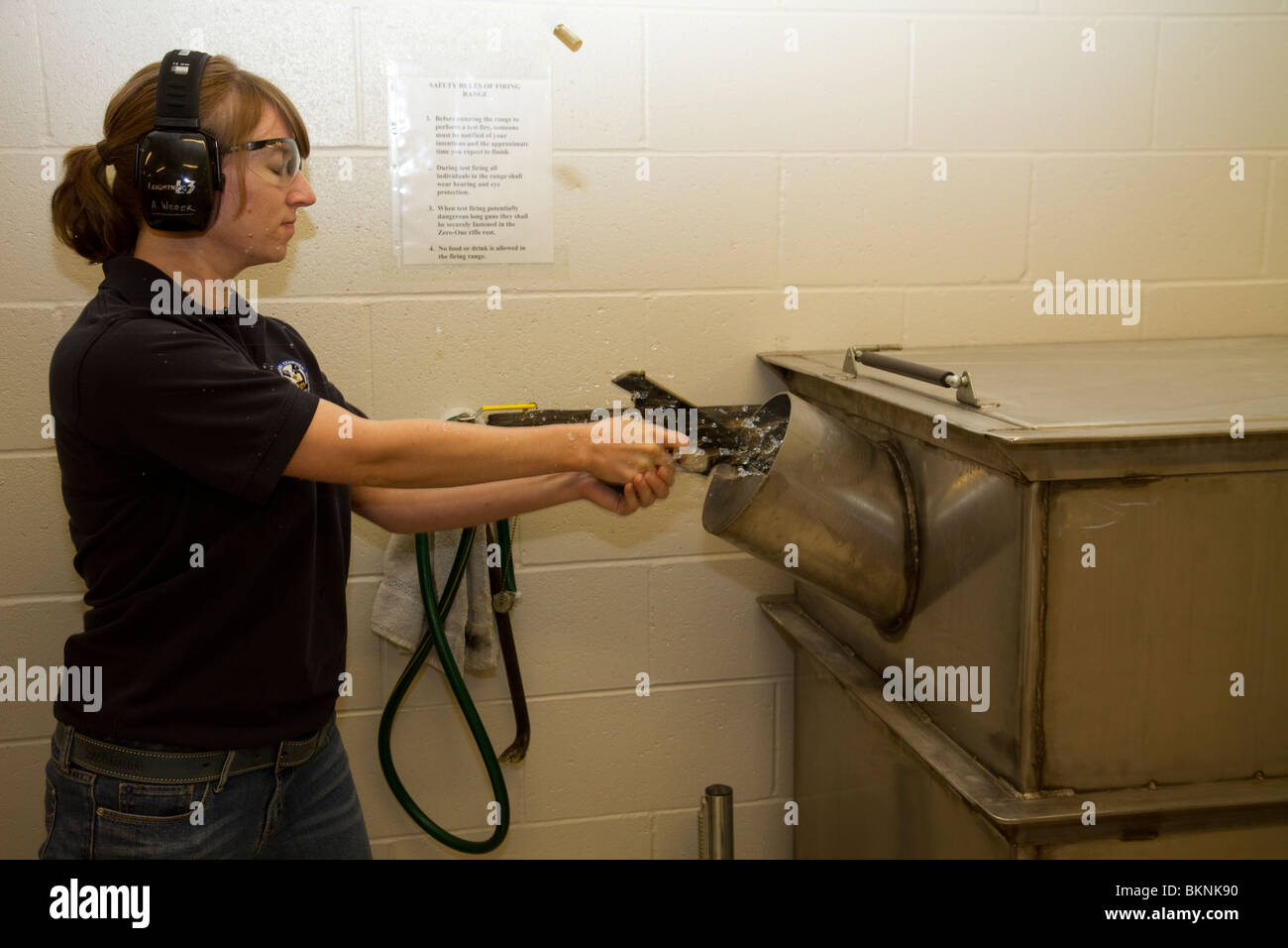 Forensic expert firing a gun into a ballistic water tank. Bullets are ...
