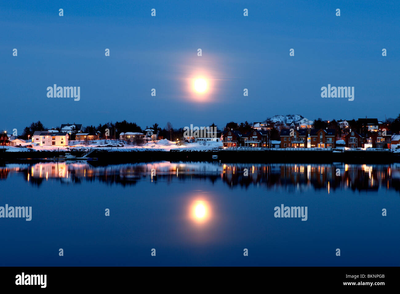 Houses reflected across the harbour of Ballstad fishing village on ...