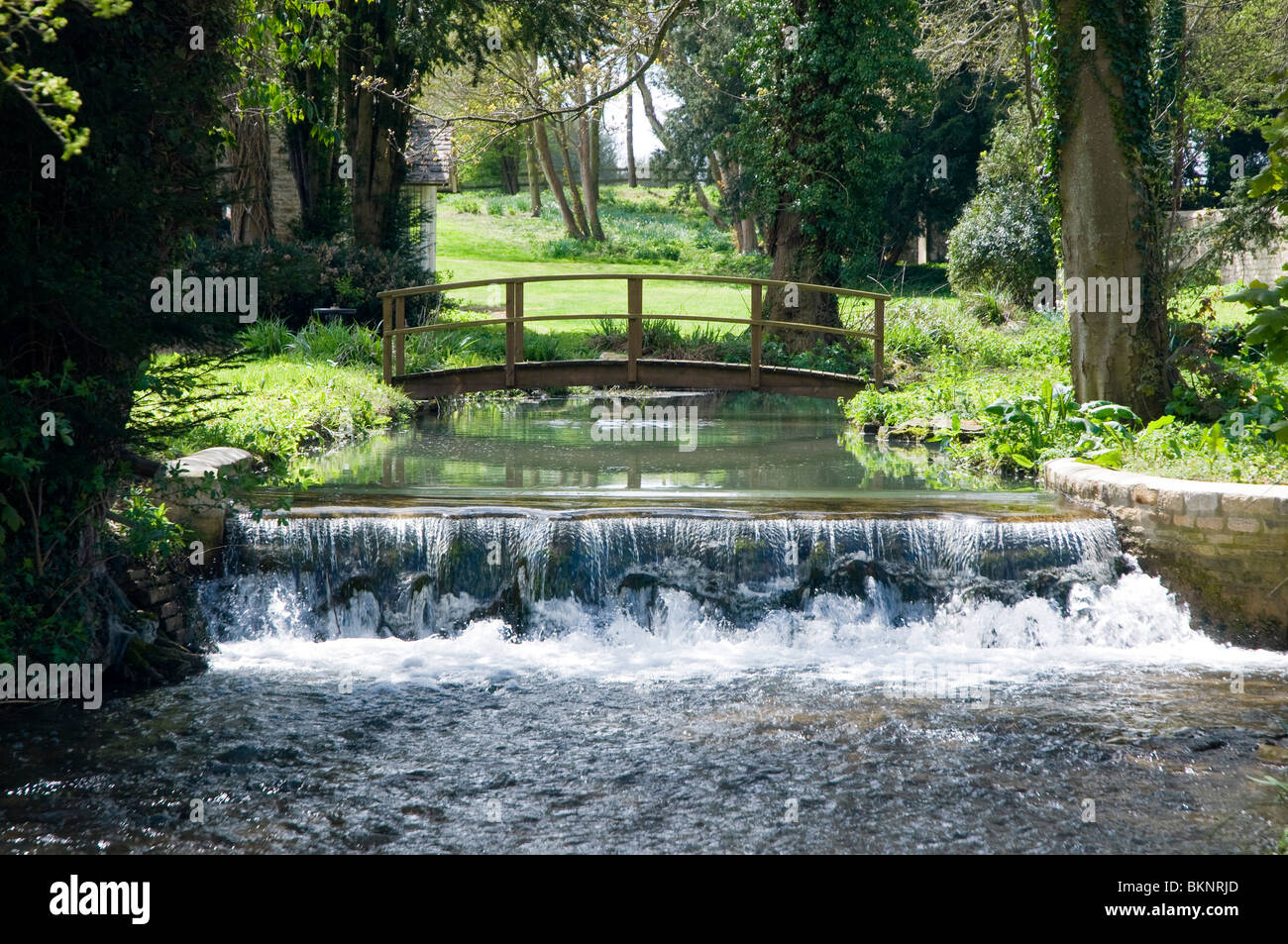 The river Glyme at Glympton, Oxfordshire, with a footbridge and small ...