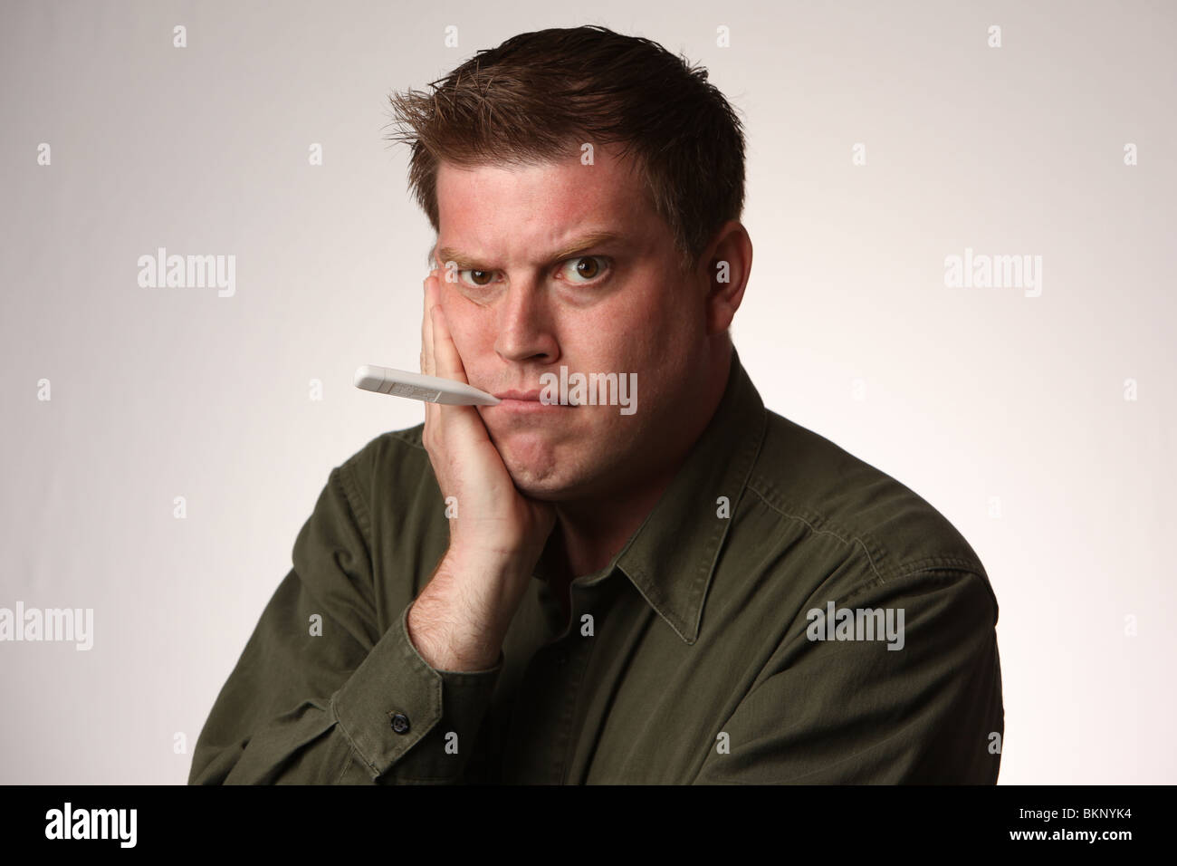 Sick man with fever taking his temperature with digital thermometer in ... Sick man with fever taking his temperature with digital thermometer in ...