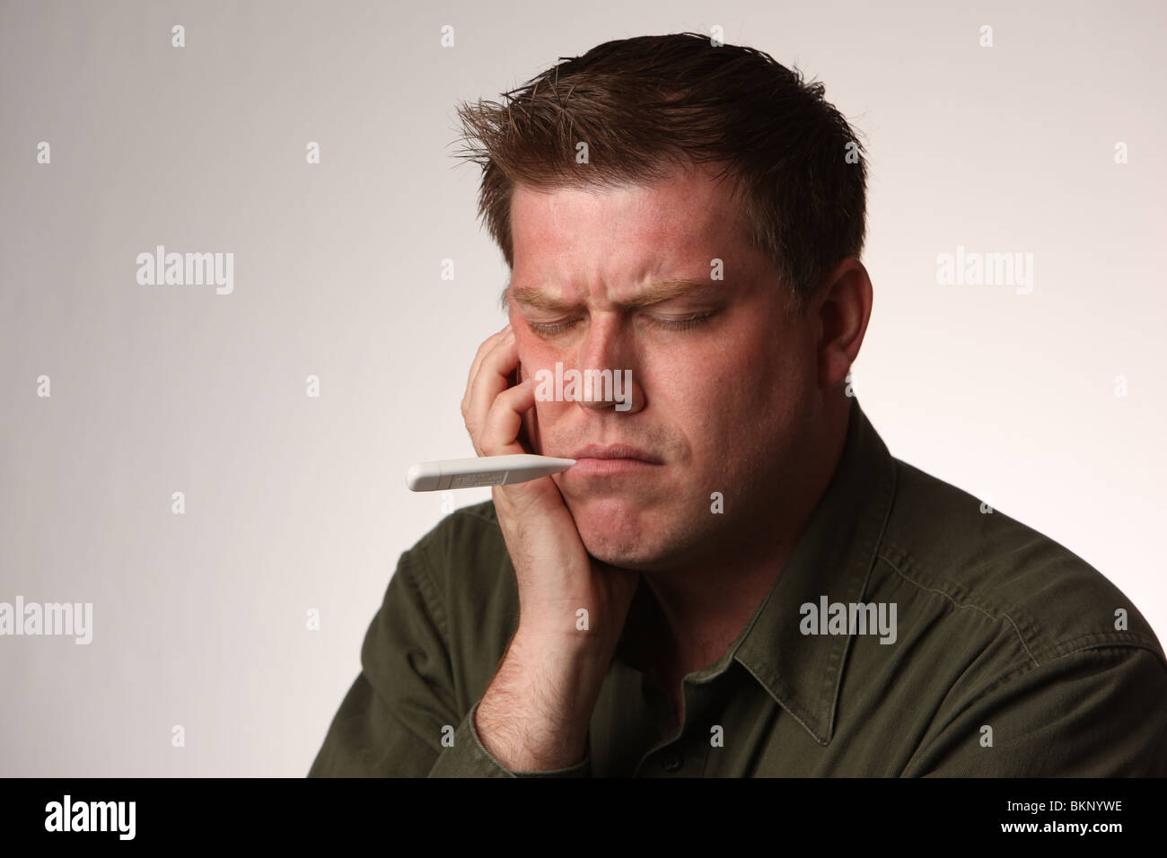 Sick man with fever taking his temperature with digital thermometer in ... Sick man with fever taking his temperature with digital thermometer in ...