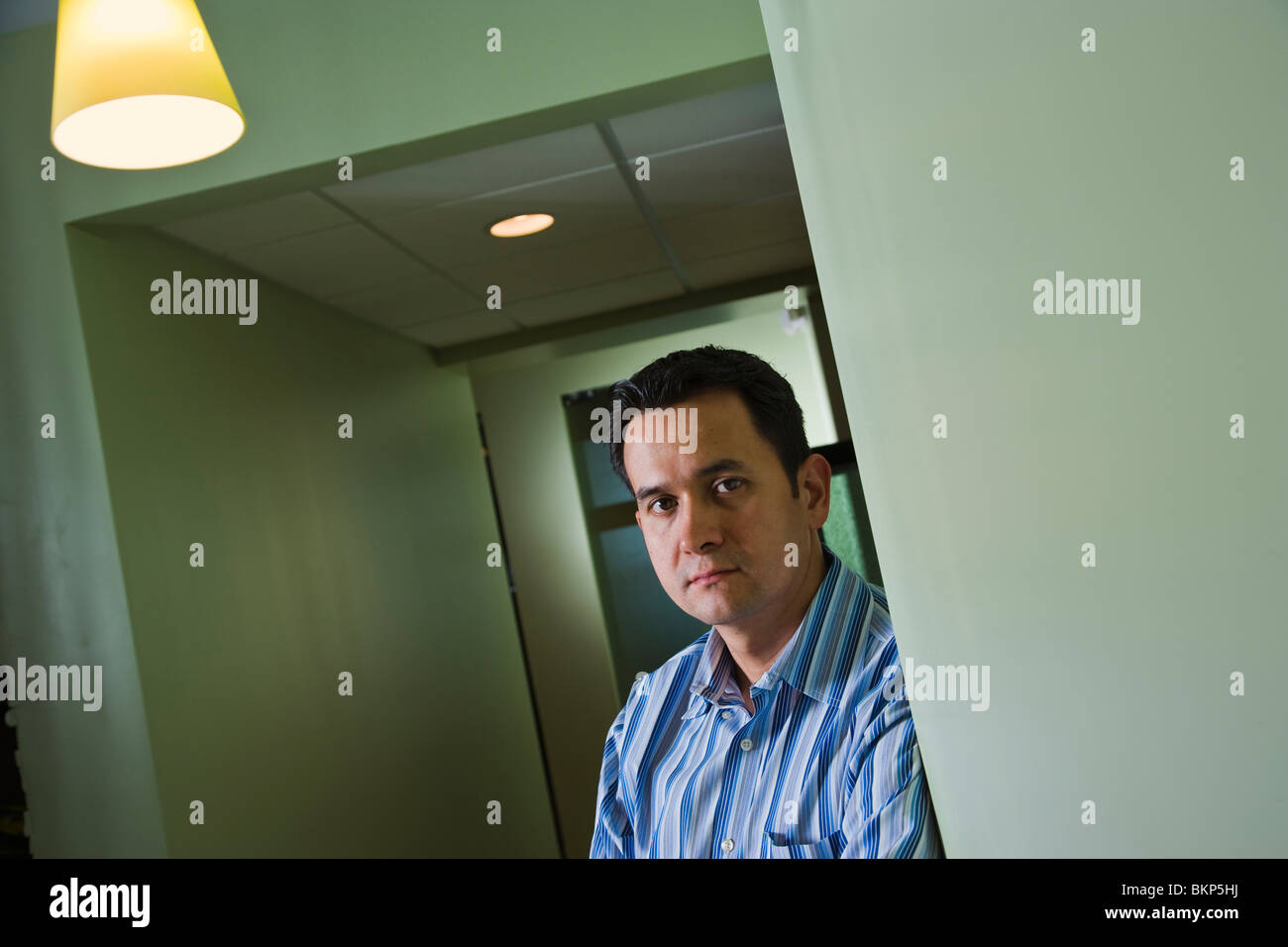 Businessman leaning against wall in office corridor Stock Photo - Alamy
