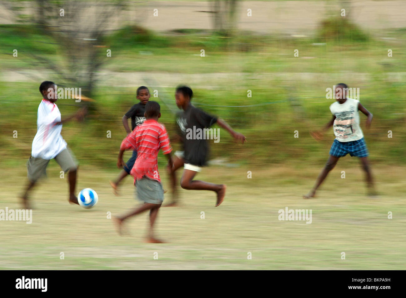 African children playing soccer barefoot in a field in Hout Bay in Cape ...